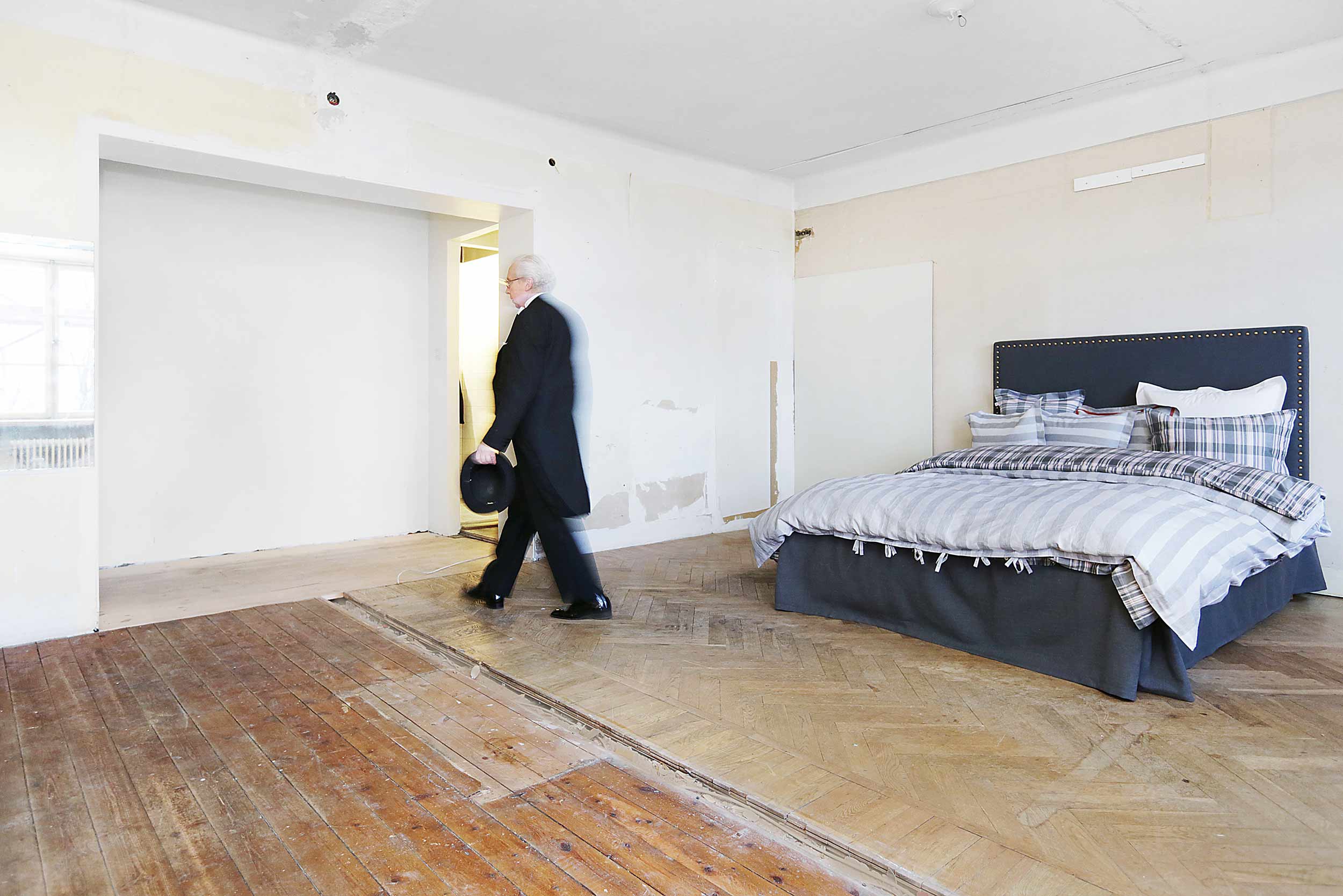 Bild interiör bostad, säng och mäklare som poserar i frack